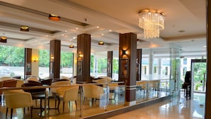 Um hall amplo com guarda-corpo de vidro, móveis modernos e um lustre.