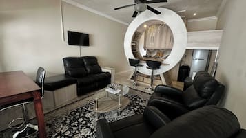 Uma sala de estar moderna com sofá, cadeiras, mesa de centro e televisão.