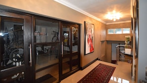 Um corredor com porta de madeira, um quadro na parede e um tapete vermelho.