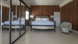 Quarto moderno com uma cama grande, mesa de cabeceira, uma cadeira e um guarda-roupa com espelho.