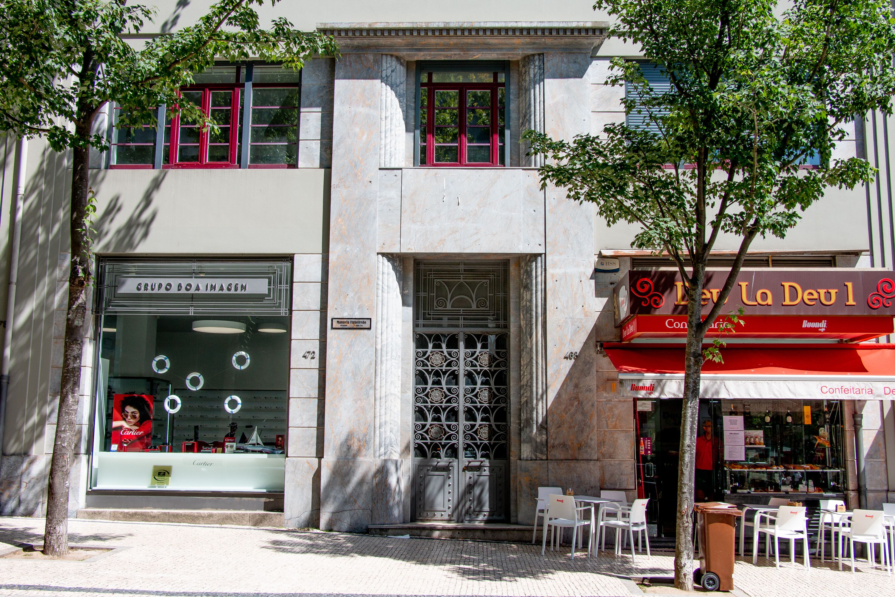 Um edifício com fachada que apresenta um toldo vermelho e uma placa com o texto 