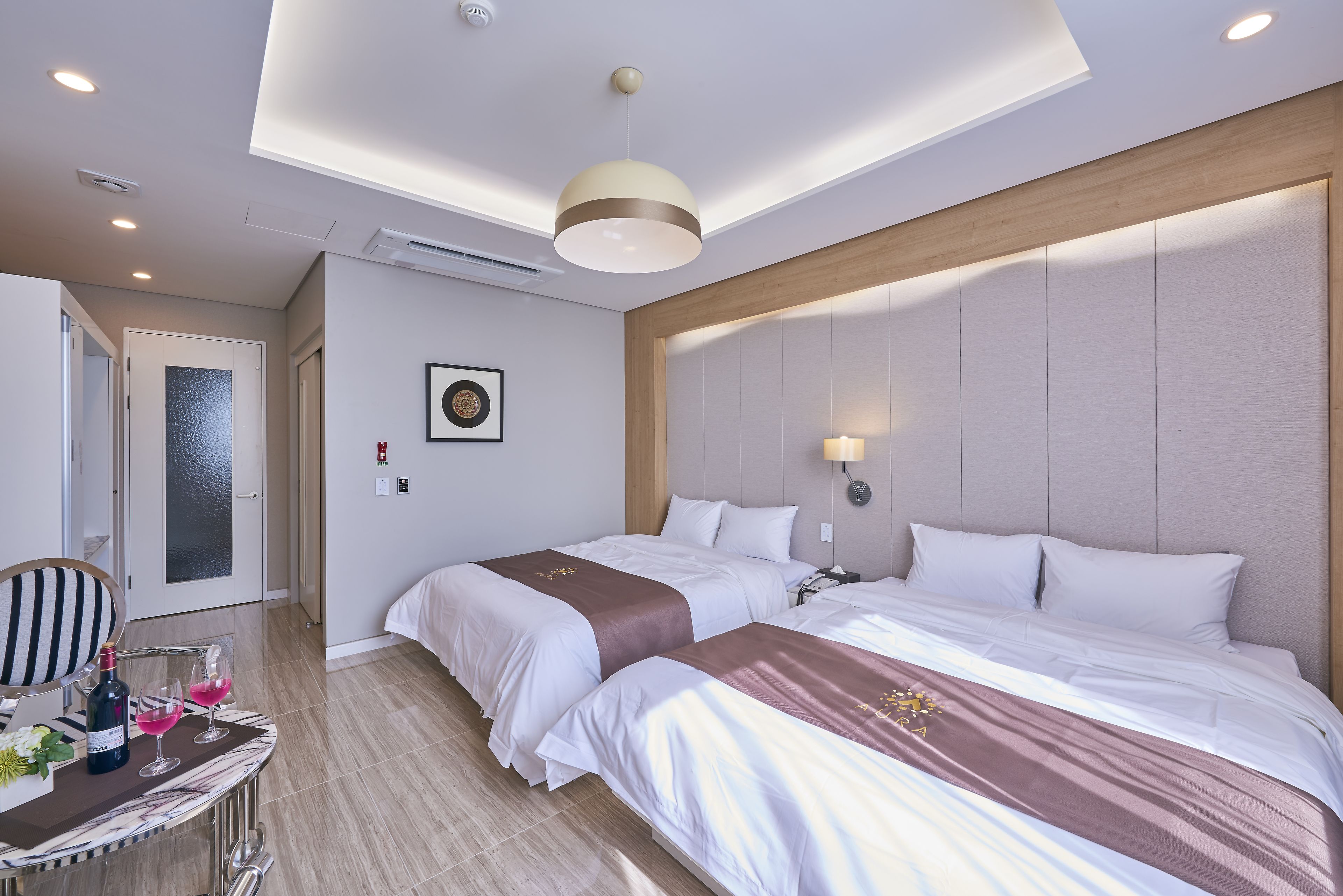 Quarto de hotel com duas camas, uma mesa de trabalho com cadeira e um minibar.