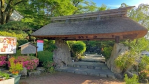 Um tradicional portão torii japonês conduzindo a um caminho de pedra, rodeado por vegetação exuberante e plantas floridas.