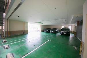 Garagem de estacionamento com piso verde, vários carros estacionados e parede revestida em azulejos.