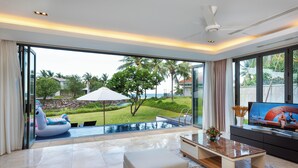 Uma sala de estar moderna com uma televisão grande, assentos confortáveis e vista para uma piscina e um jardim.