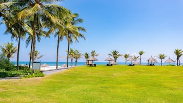 Praia particular, areia branca, espreguiçadeiras, guarda-sóis