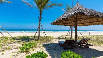 Praia particular, areia branca, espreguiçadeiras, guarda-sóis