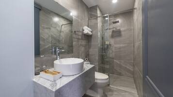 Um banheiro moderno com toucador de mármore, vaso sanitário e chuveiro com parede de vidro.
