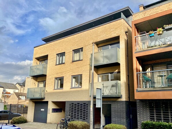 Um edifício residencial com vários andares, varandas, uma porta de garagem e uma placa visível.