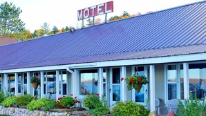 Um motel com telhado de metal corrugado, parede de pedra e uma placa.