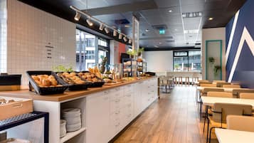 Um café moderno com balcão de buffet, área de estar e vista para a paisagem urbana.
