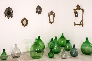 Conjunto de objetos decorativos, incluindo espelhos e vasos de vidro, em uma parede.