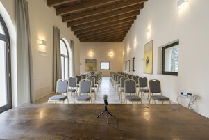 Uma sala de conferências com uma mesa de madeira, cadeiras e um suporte para microfone.