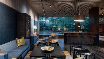 Interior moderno com sofá, mesa de jantar e bar, apresentando uma grande janela e teto decorativo.