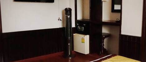 Quarto de hotel com uma cama, uma televisão de tela plana na parede, um refrigerador pequeno e um espelho sobre a porta.