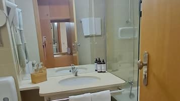 Casa de banho com cabine de duche em vidro, lavatório com espelho e sanita.