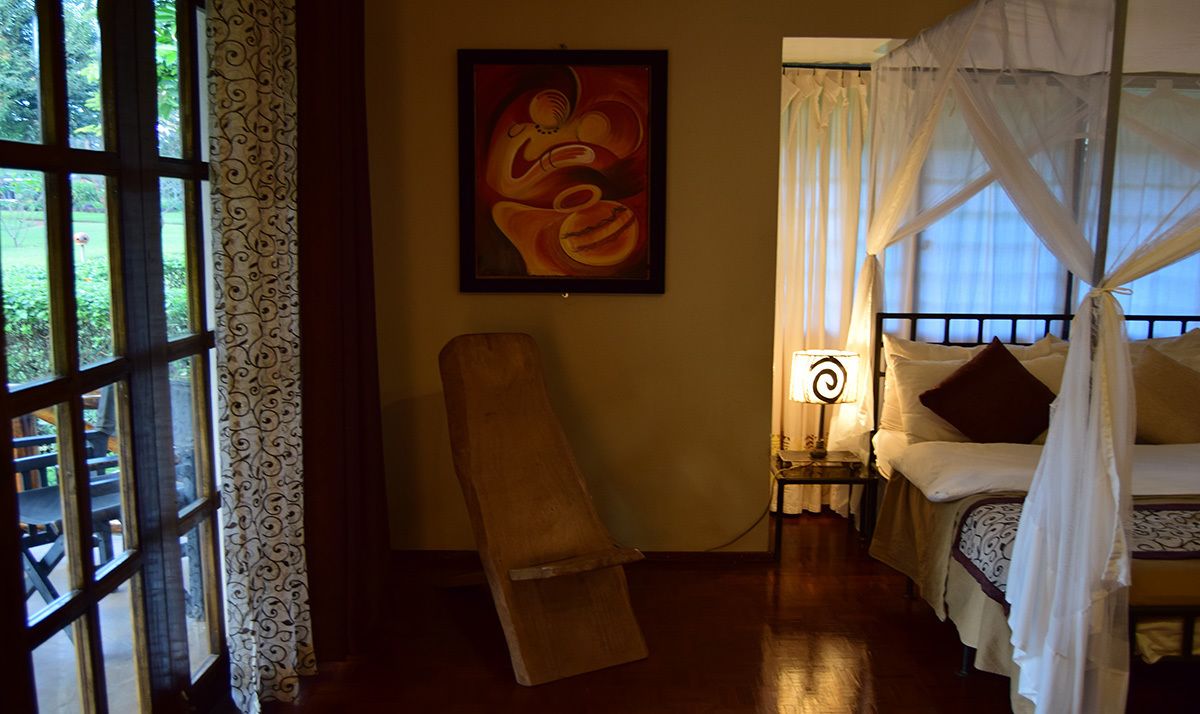 Quarto com cama, cadeira, quadro e janela com cortinas.