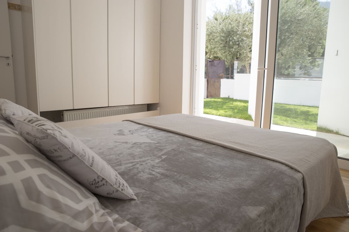 Quarto com cama, janela grande e vista para o exterior.