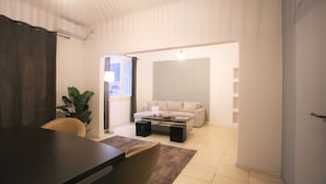 Uma sala de estar moderna com sofá, mesa de centro e um espaço de jantar com mesa e cadeiras.