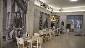 Um restaurante com um balcão comprido, várias cadeiras e um cartaz grande na parede.
