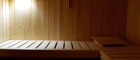 Uma sauna com bancos de madeira e uma luminária fixada na parede.