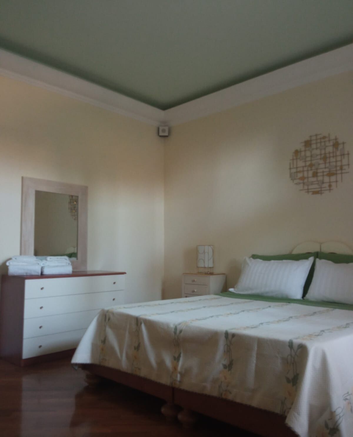 Quarto com cama, penteadeira, mesa de cabeceira e espelho.