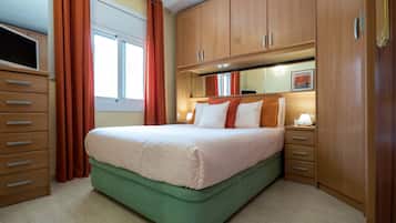 Quarto com cama, armários de madeira, cômoda e janela com cortinas.