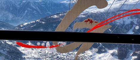 Um teleférico com um logotipo e o texto "GEMMIPA 2350" ao fundo de uma montanha coberta de neve.