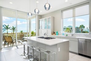 Cozinha moderna com uma ilha grande, banquetas e vista para o oceano.