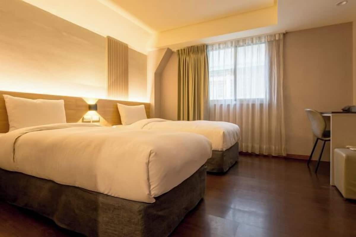 Quarto de hotel com uma cama grande, uma escrivaninha e uma cadeira.