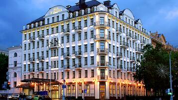 Um hotel grande, de vários andares, com estilo arquitetônico europeu clássico, apresentando várias varandas e uma entrada notável com área coberta.
