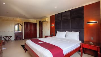Quarto de hotel com uma cama grande, uma escrivaninha, uma cadeira e um guarda-roupa.