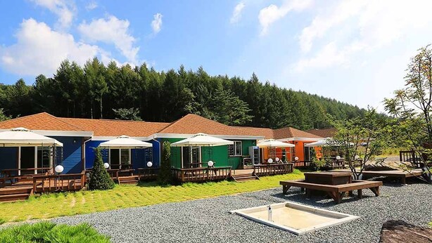 Fileira de cabanas coloridas com área de estar externa e piscina.