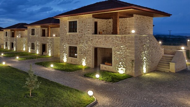 Um edifício de pedra com várias divisões, um espaço coberto ao ar livre e um caminho de acesso pavimentado.