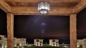 Uma área externa coberta com parede de pedra e luminária pendente.