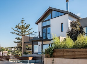 Uma casa moderna de dois andares com varanda, piscina e jardim.