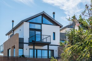 Uma casa moderna de dois andares com varanda, janelas amplas e chaminé.