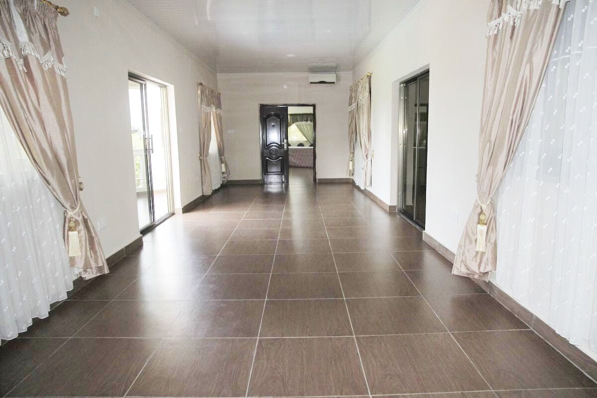 Um corredor de hotel com chão de azulejos, uma porta no final e cortinas nas paredes.