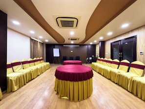 Sala de conferência com cadeiras amarelas, uma mesa central e um quadro branco.