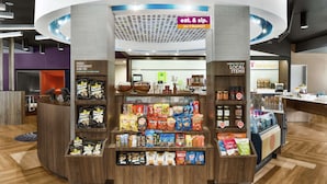 Uma lanchonete com diversos snacks embalados e um aviso indicando um mercado 24 horas.