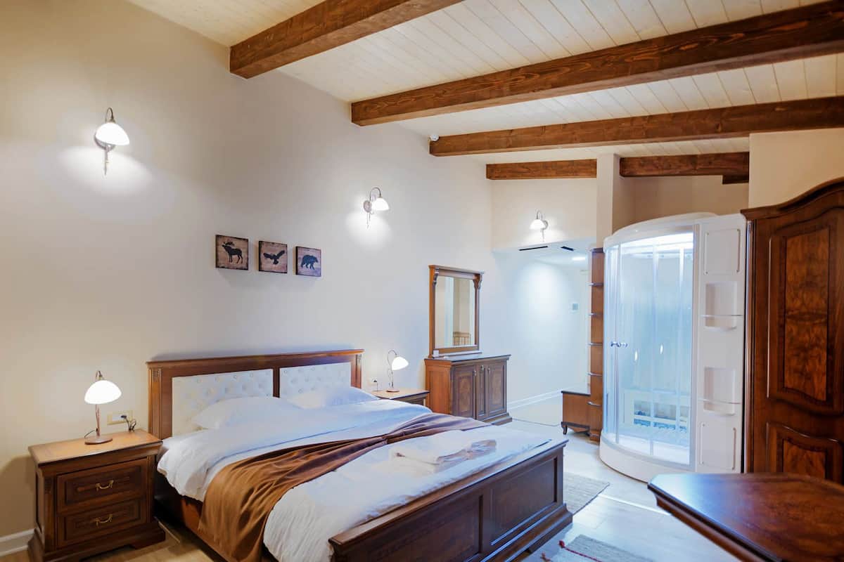 Quarto com cama de madeira, mesas de cabeceira, guarda-roupa e espelho.