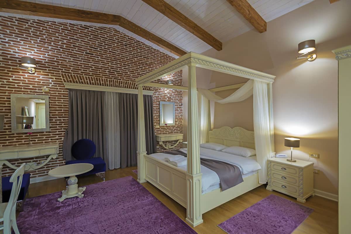 Quarto com cama de dossel, penteadeira com espelho, mesinha e cadeira.