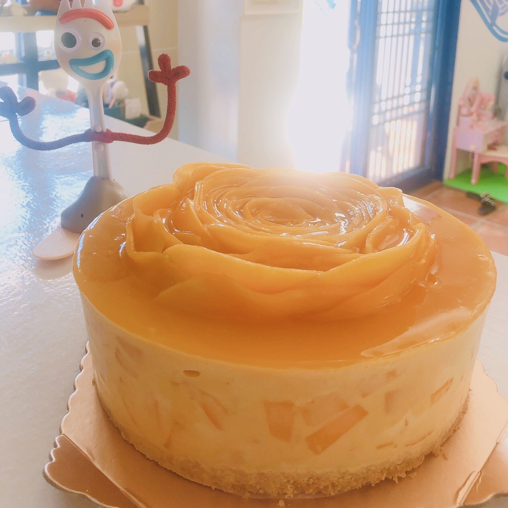 Um cheesecake com cobertura de caramelo lisa e brilhante, sobre um prato branco em uma mesa de madeira.