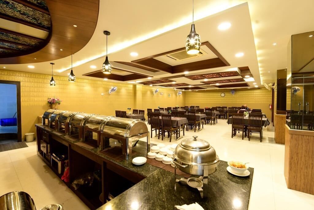 Uma área de buffet com várias estações de comida, mesas e cadeiras dispostas para refeições.