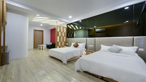 Quarto de hotel moderno com duas camas, piso de madeira, parede com detalhes em vermelho e um espelho grande.