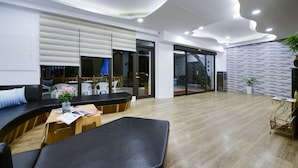 Um hall de hotel moderno com área de estar, piso de madeira e parede texturizada.