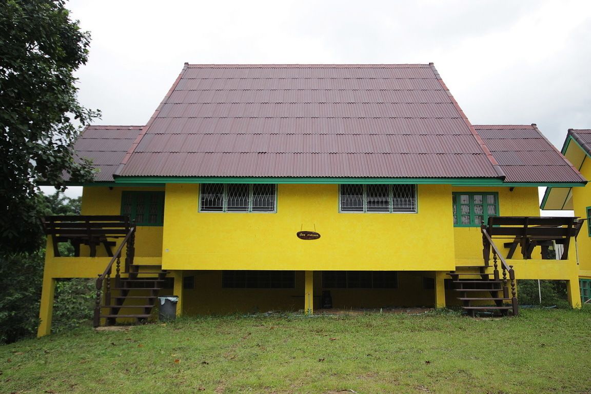 Um edifício amarelo com telhado castanho, molduras de janela verdes e uma placa com a inscrição 'The Retreat'.