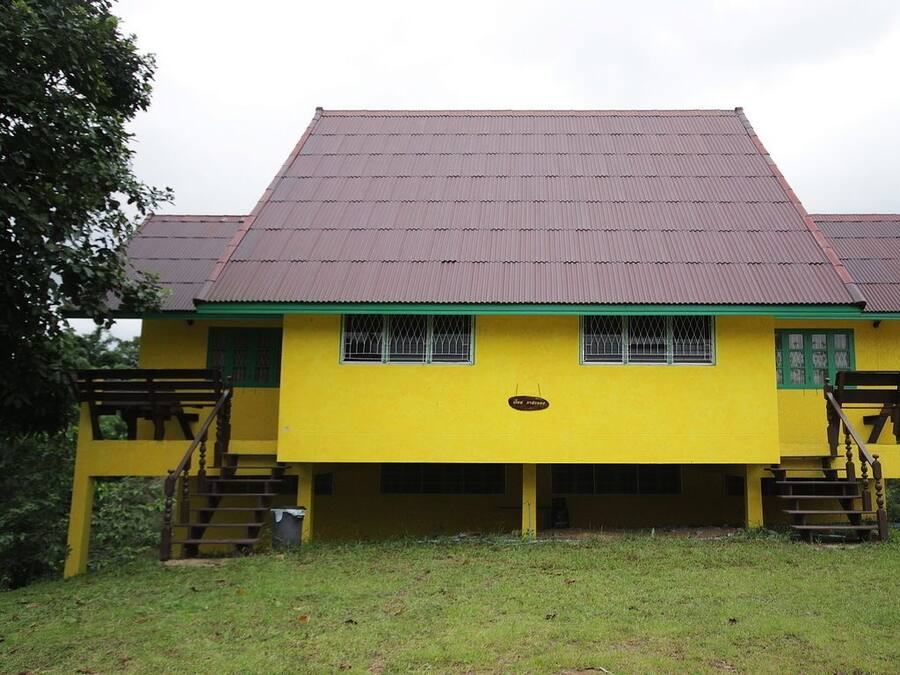 Um edifício amarelo com telhado castanho, molduras de janela verdes e uma placa com a inscrição 'The Retreat'.
