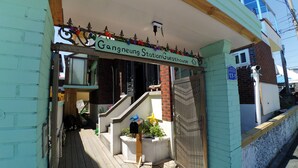 Entrada de um edifício com uma placa que diz 'Gangneung Station Guesthouse'.