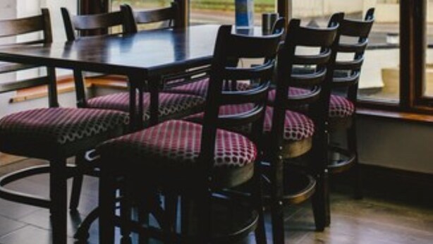 Uma área de refeições com mesa, cadeiras, janelas amplas e vista para o exterior.